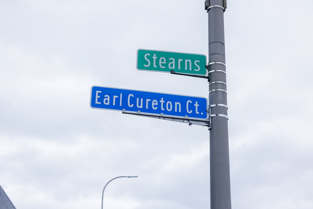 As the cloth sheet slipped off the bright blue street sign, more than ...